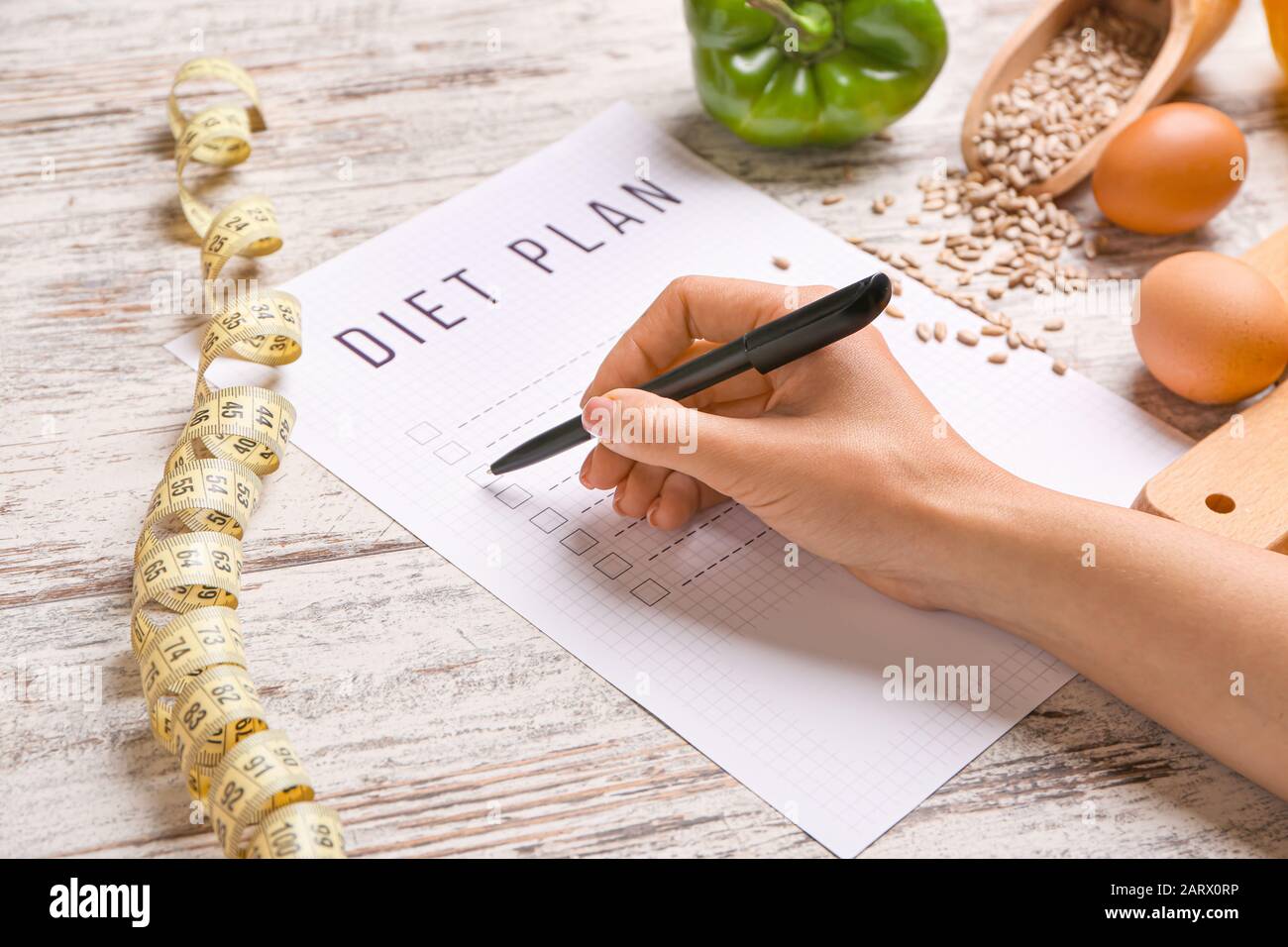 Woman writing something on sheet of paper with diet plan Stock Photo ...