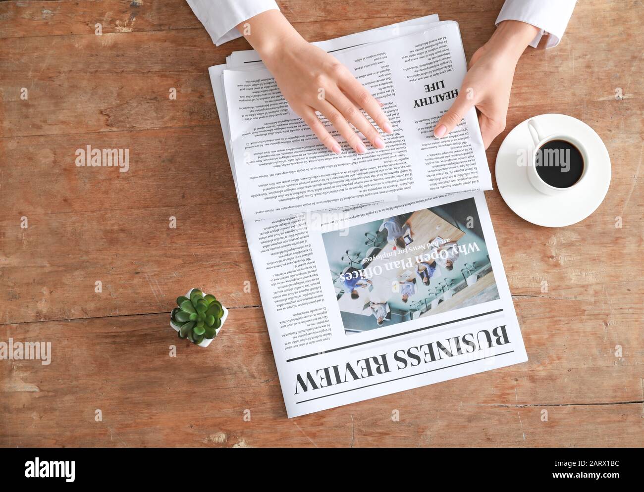 Young woman reading newspaper at table Stock Photo - Alamy
