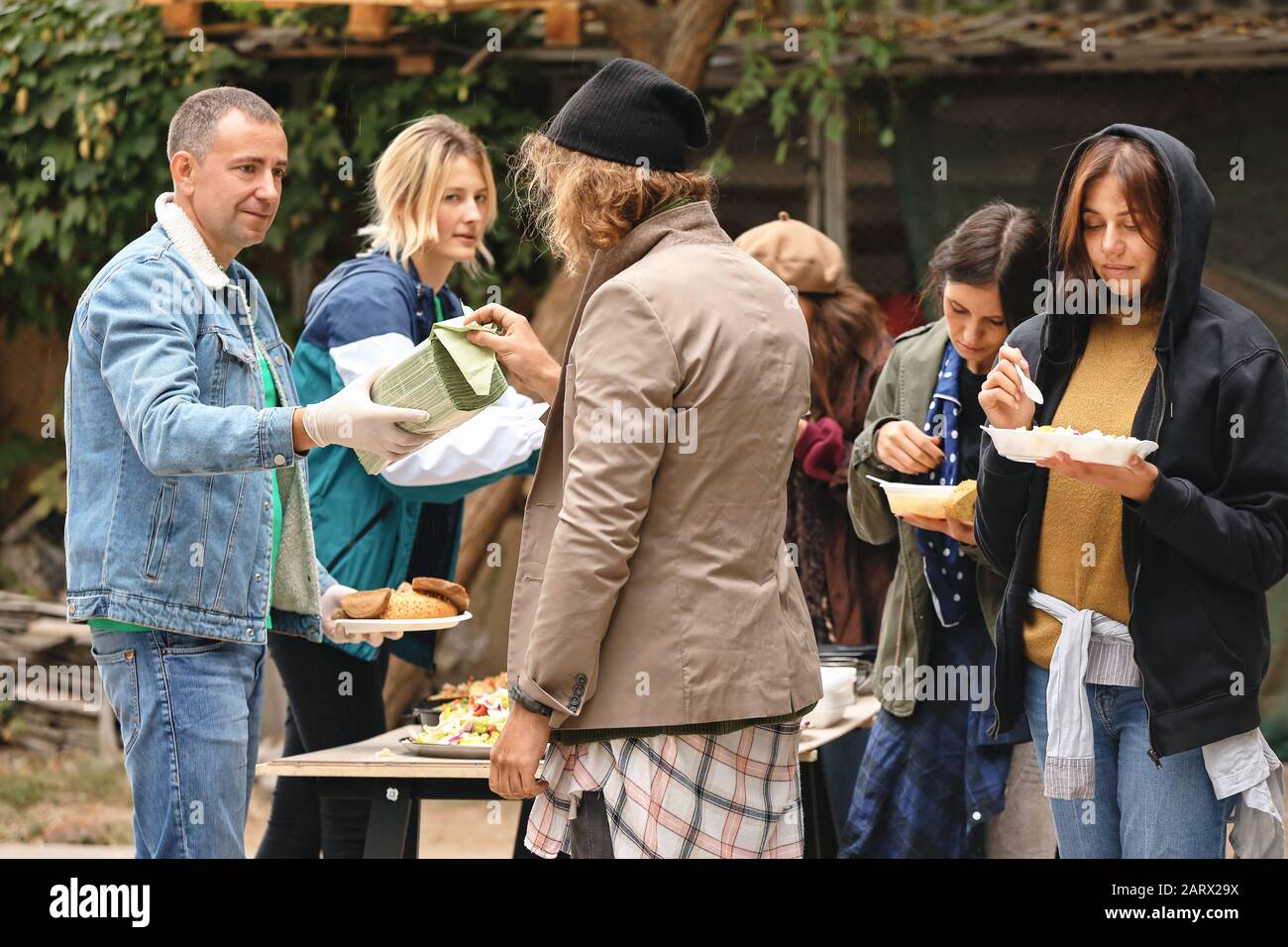 Volunteers giving food to homeless people outdoors Stock Photo - Alamy