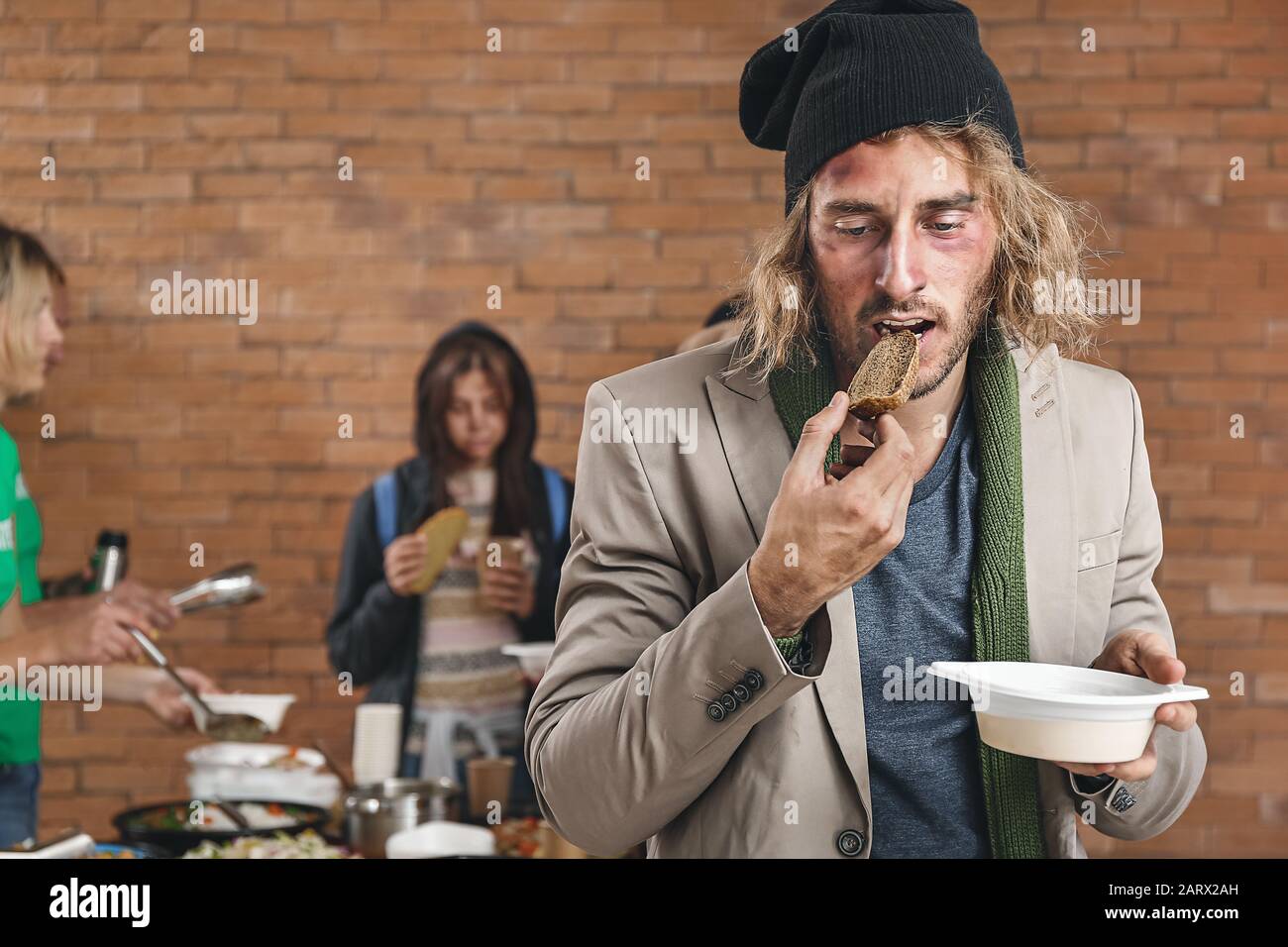 Hungry homeless man eating food received from volunteers Stock Photo ...