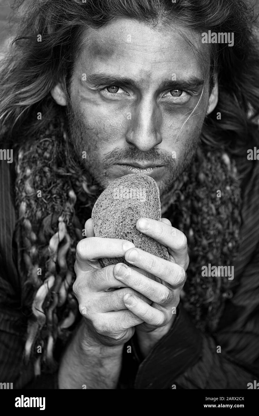 Black and white portrait of poor homeless man with piece of bread ...
