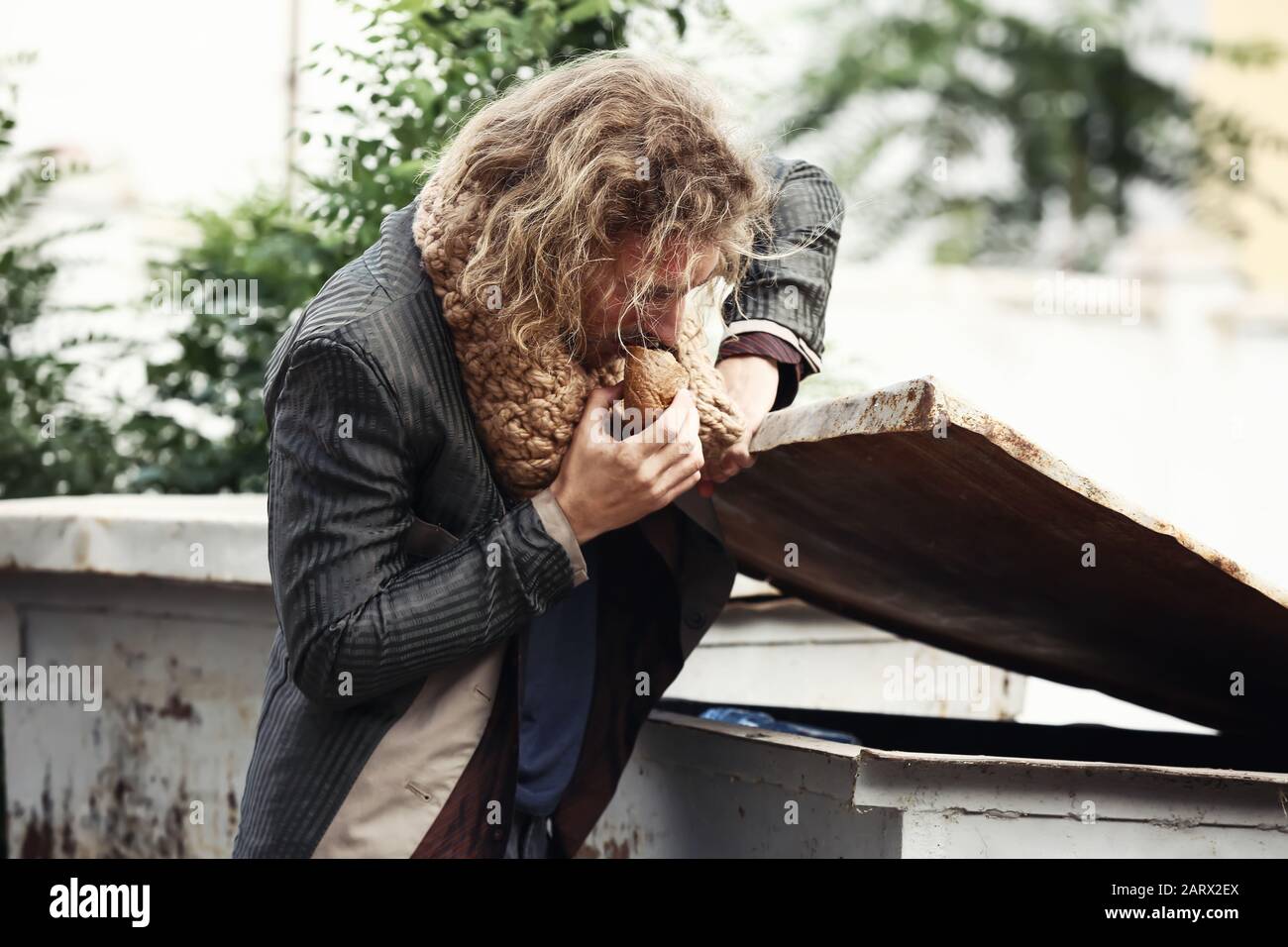 Poor homeless man looking for food in garbage toter outdoors Stock ...