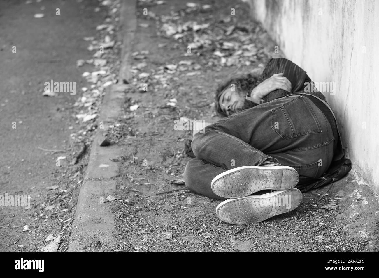 Black and white photo of poor homeless man sleeping on ground outdoors ...
