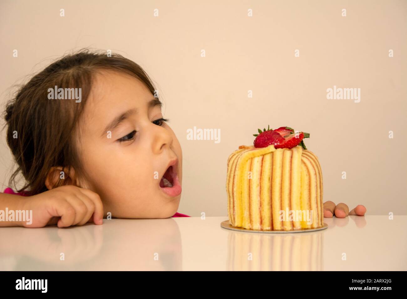 Little girl looking at cake and is surprised Stock Photo - Alamy