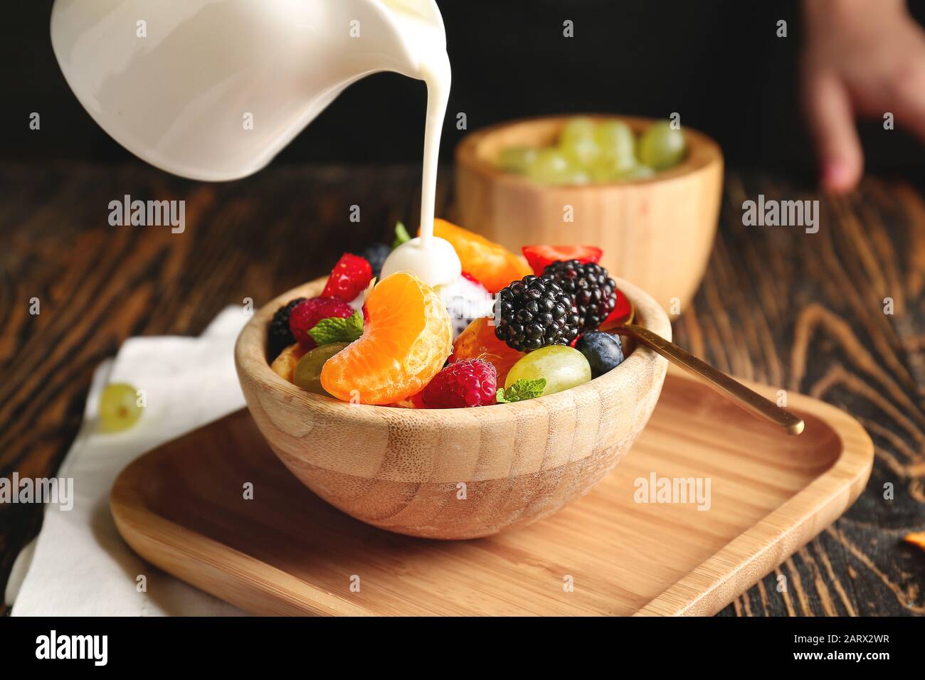 Pouring of yogurt from jug onto tasty fruit salad, closeup Stock Photo ...