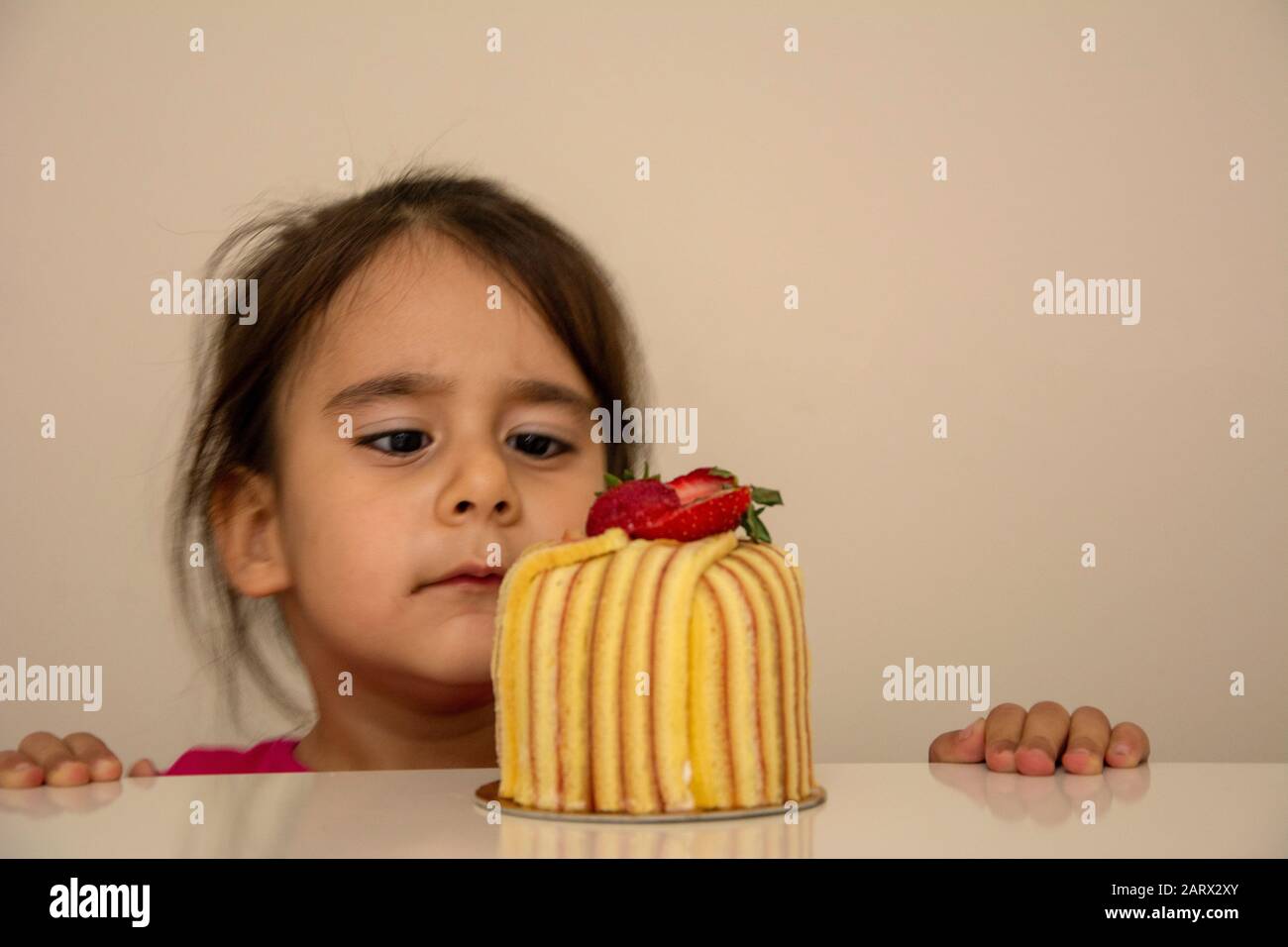 Little girl looking at cake and is surprised Stock Photo - Alamy