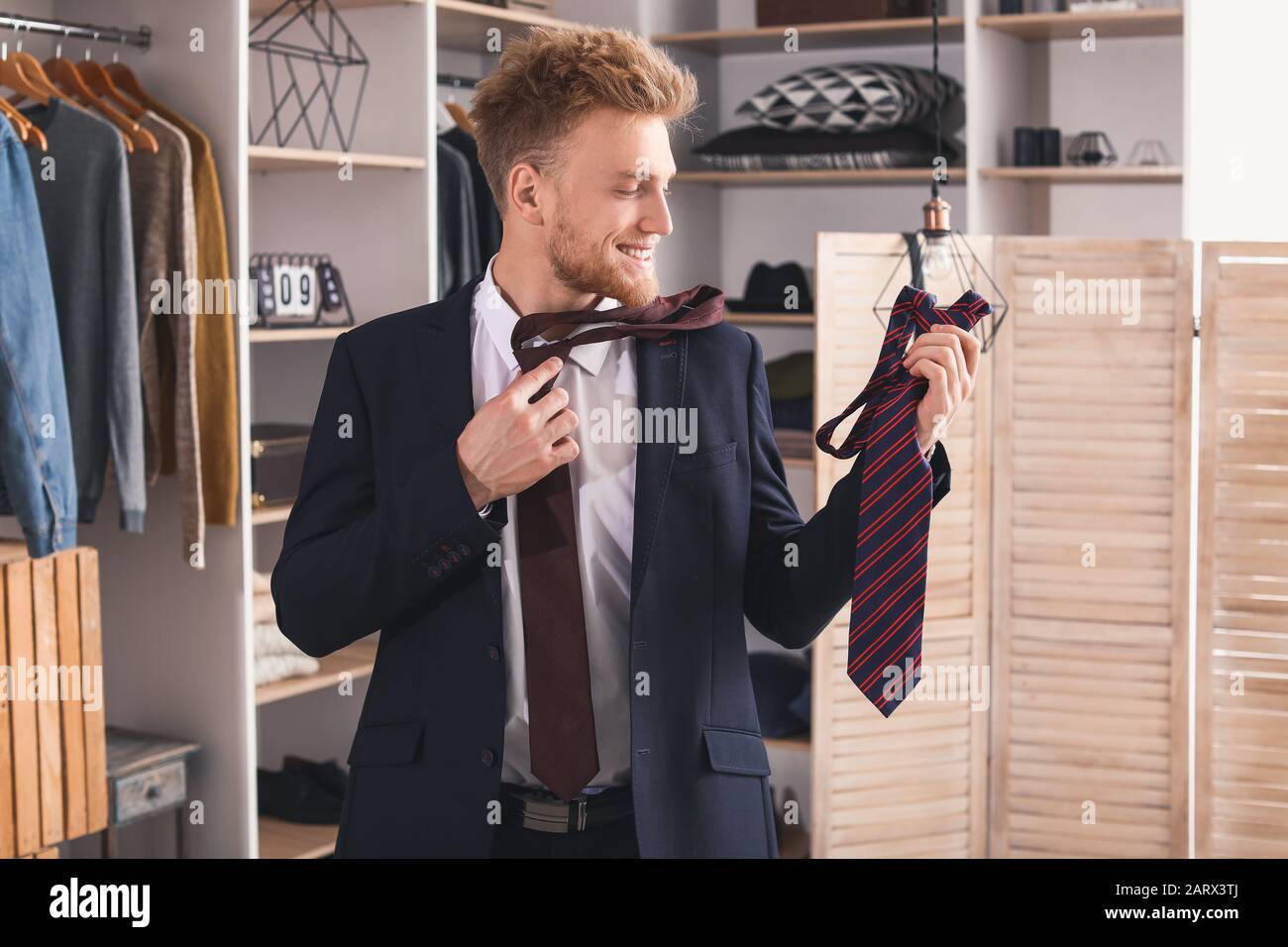 Handsome man choosing necktie in dressing room Stock Photo - Alamy