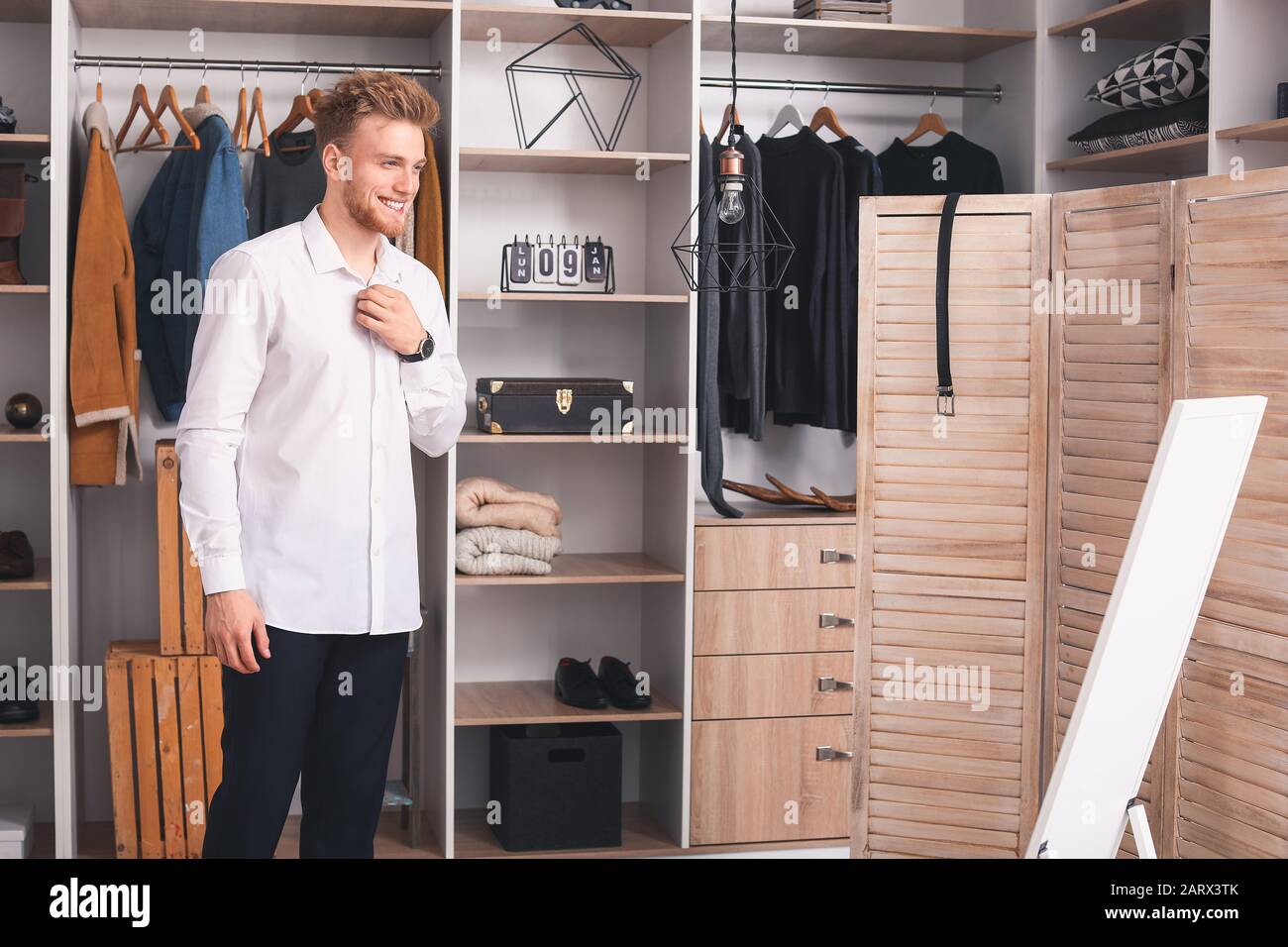 Handsome man trying on stylish clothes in dressing room Stock Photo - Alamy