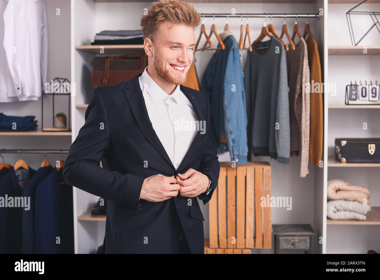Handsome man trying on stylish clothes in dressing room Stock Photo - Alamy