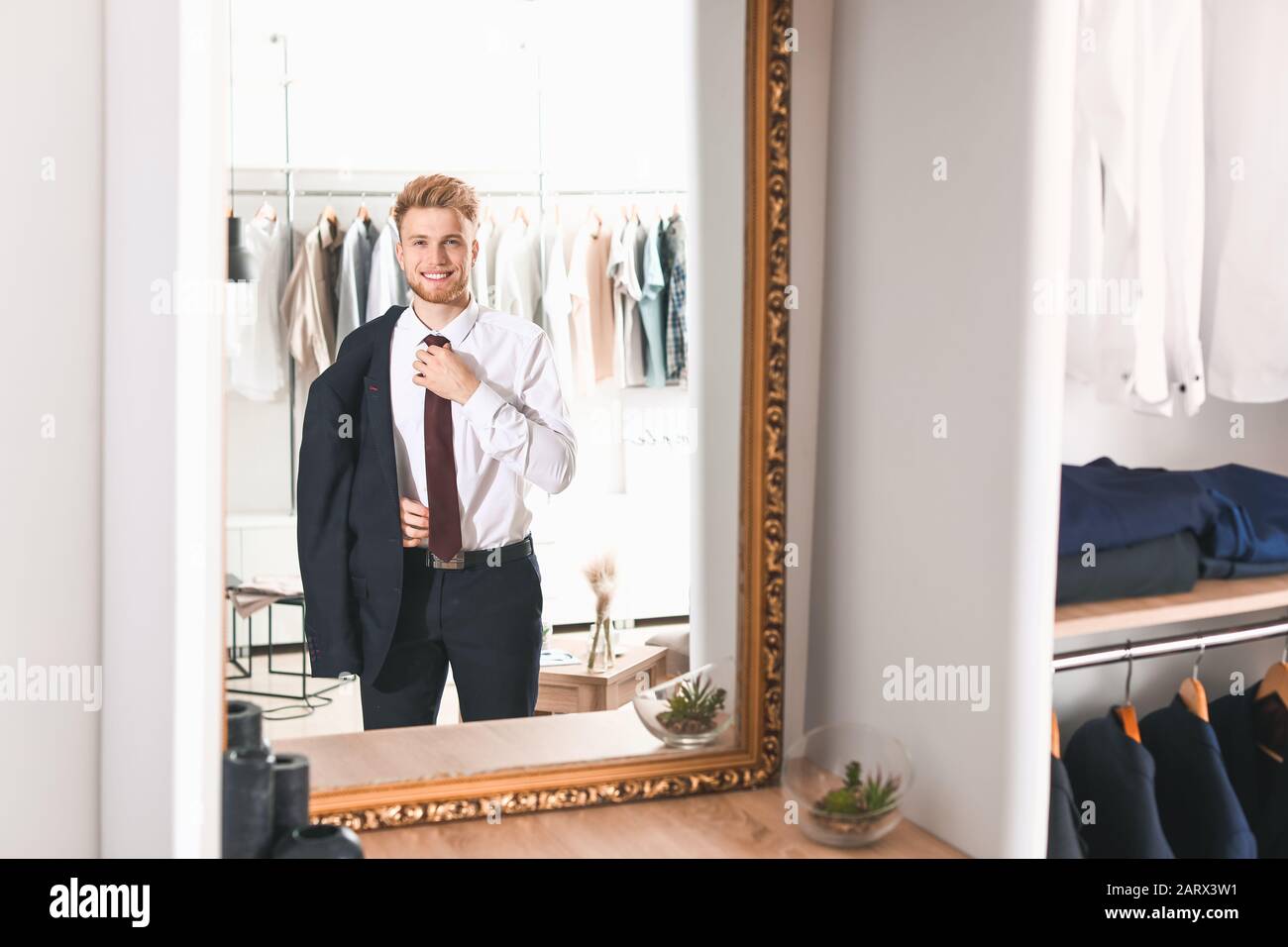 Handsome man trying on stylish clothes in dressing room Stock Photo - Alamy