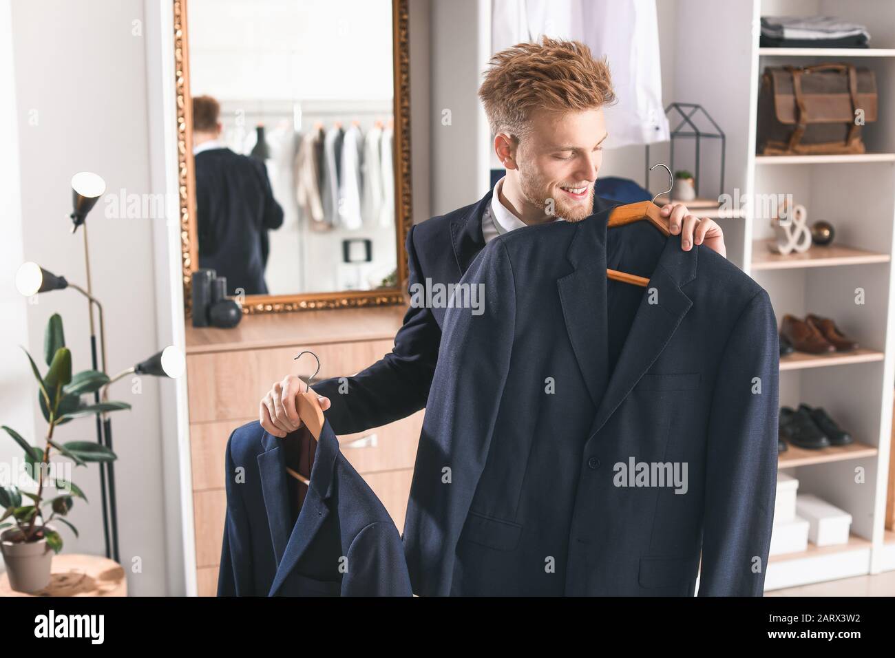 Handsome man choosing clothes in dressing room Stock Photo - Alamy