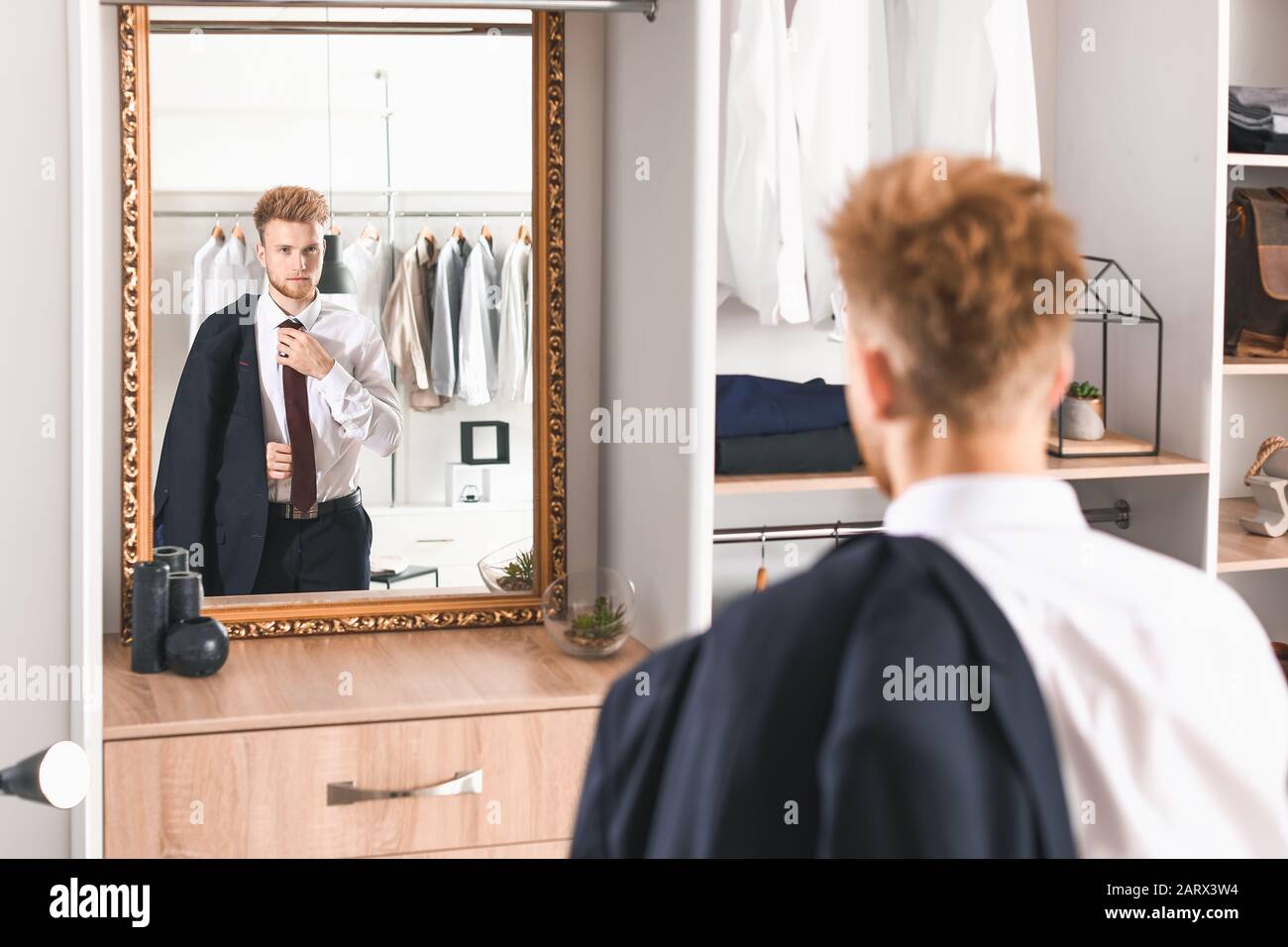 Handsome man trying on stylish clothes in dressing room Stock Photo - Alamy