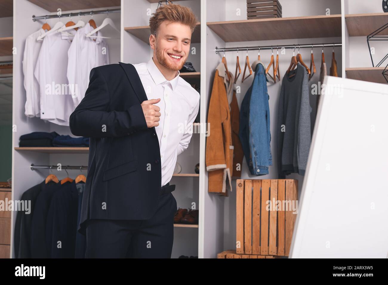 Handsome man trying on stylish clothes in dressing room Stock Photo - Alamy
