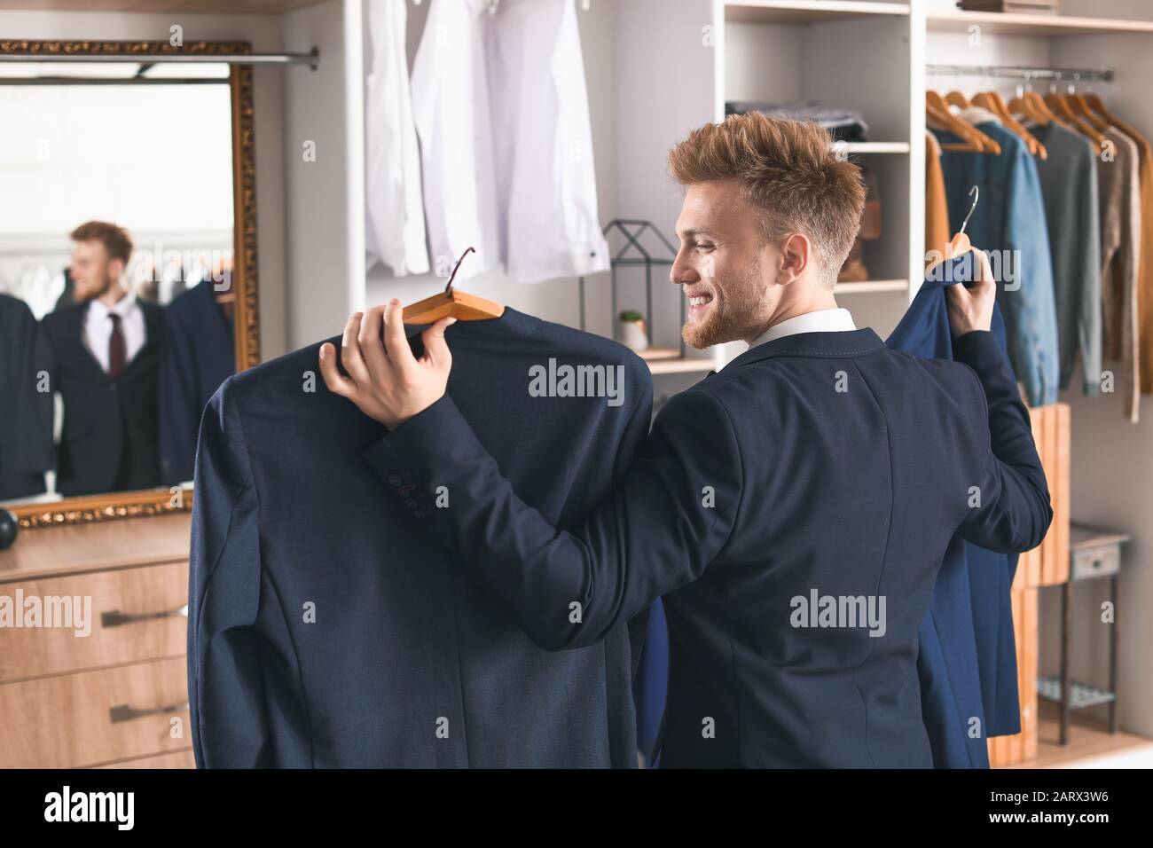 Handsome man choosing clothes in dressing room Stock Photo - Alamy