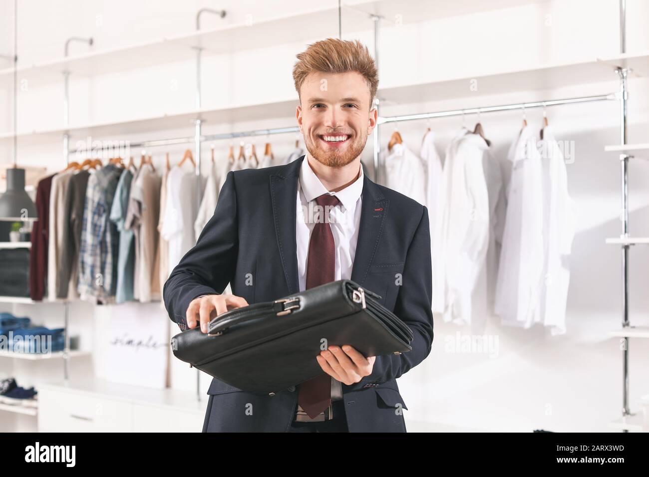 Handsome man choosing briefcase in dressing room Stock Photo - Alamy