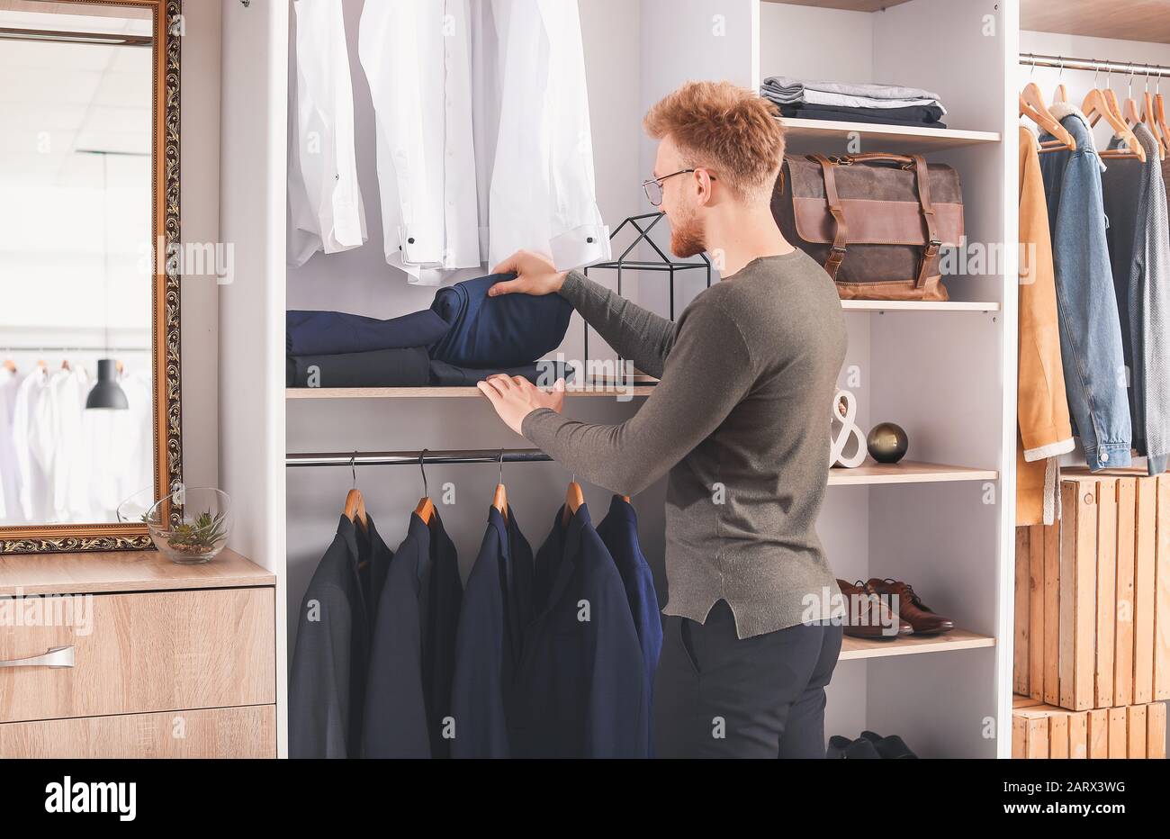Handsome man choosing clothes in dressing room Stock Photo - Alamy