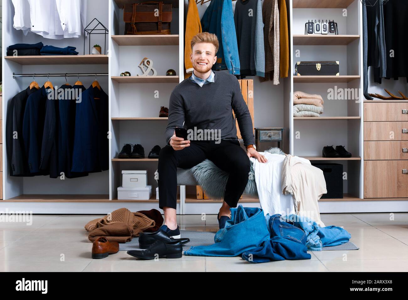 Handsome man choosing clothes in dressing room Stock Photo - Alamy