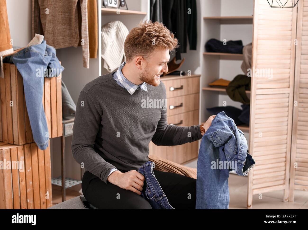 Handsome man choosing clothes in dressing room Stock Photo - Alamy
