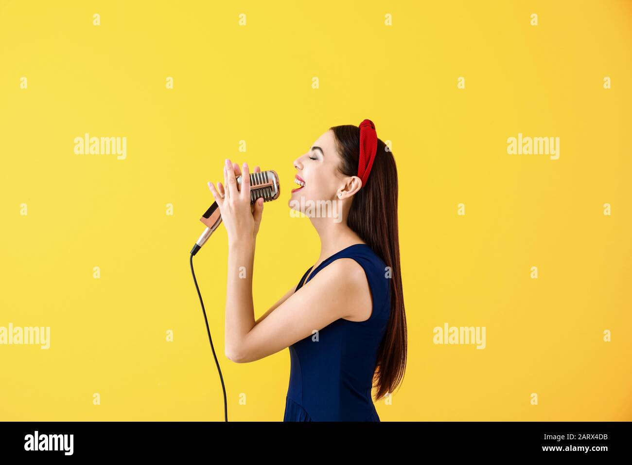Beautiful young female singer with microphone on color background Stock ...