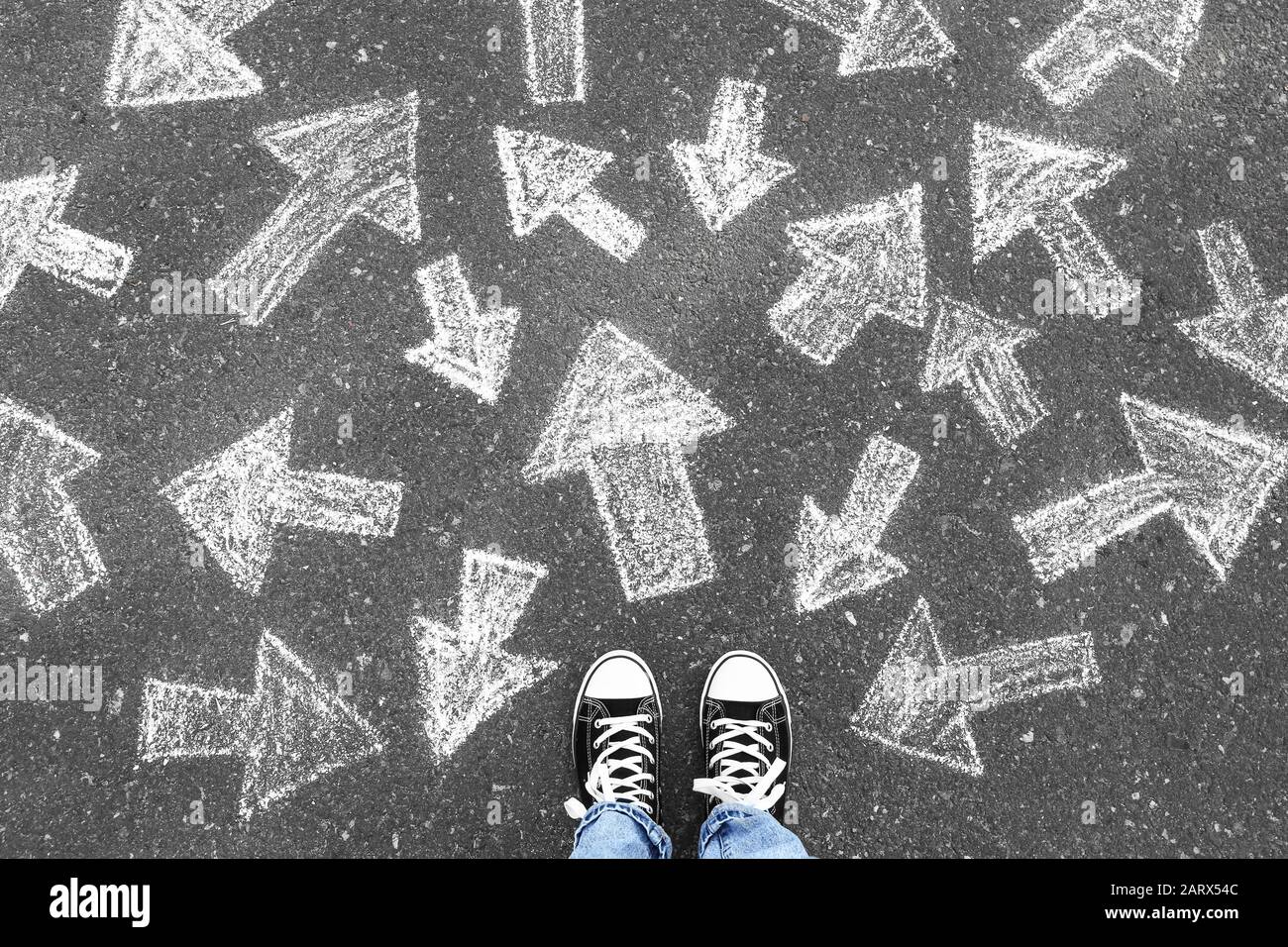 Person standing on road with arrows pointing in different directions ...