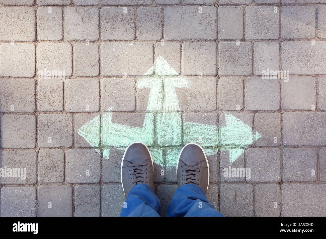Person standing on road with arrows pointing in different directions ...