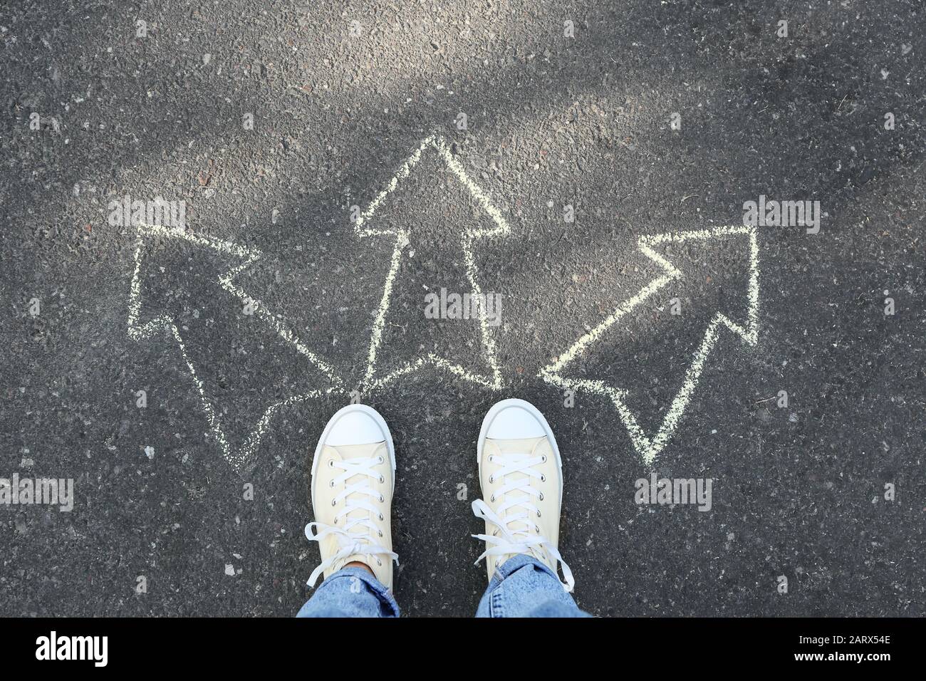 Person standing on road with arrows pointing in different directions ...