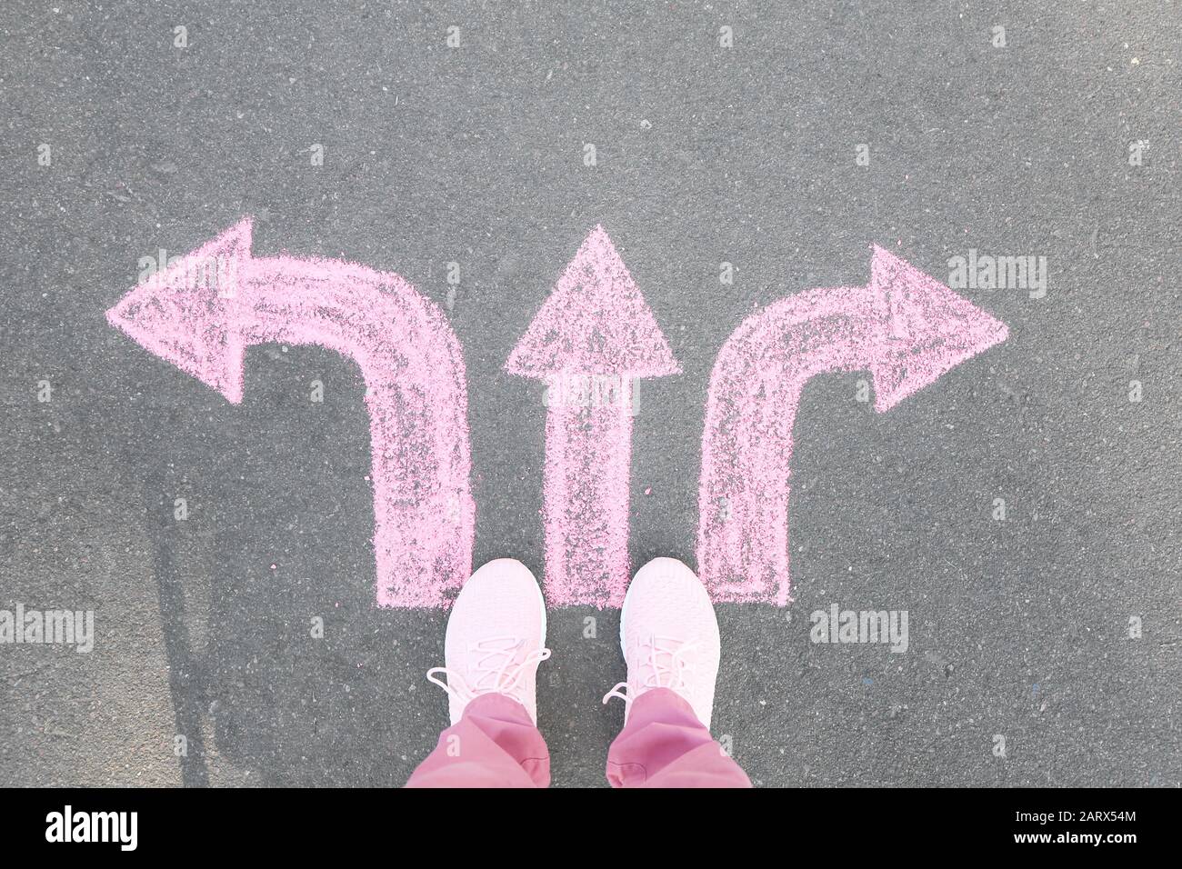 Person standing on road with arrows pointing in different directions ...