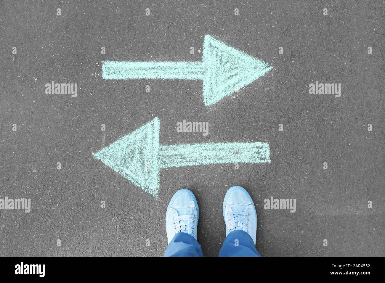 Person standing on road with arrows pointing in different directions ...