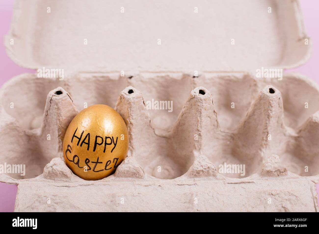 Single golden chicken egg in an open carton box with Happy Easter ...