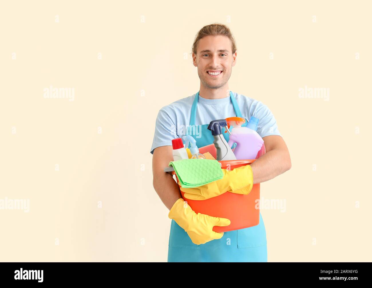 Male janitor with cleaning supplies on light background Stock Photo - Alamy