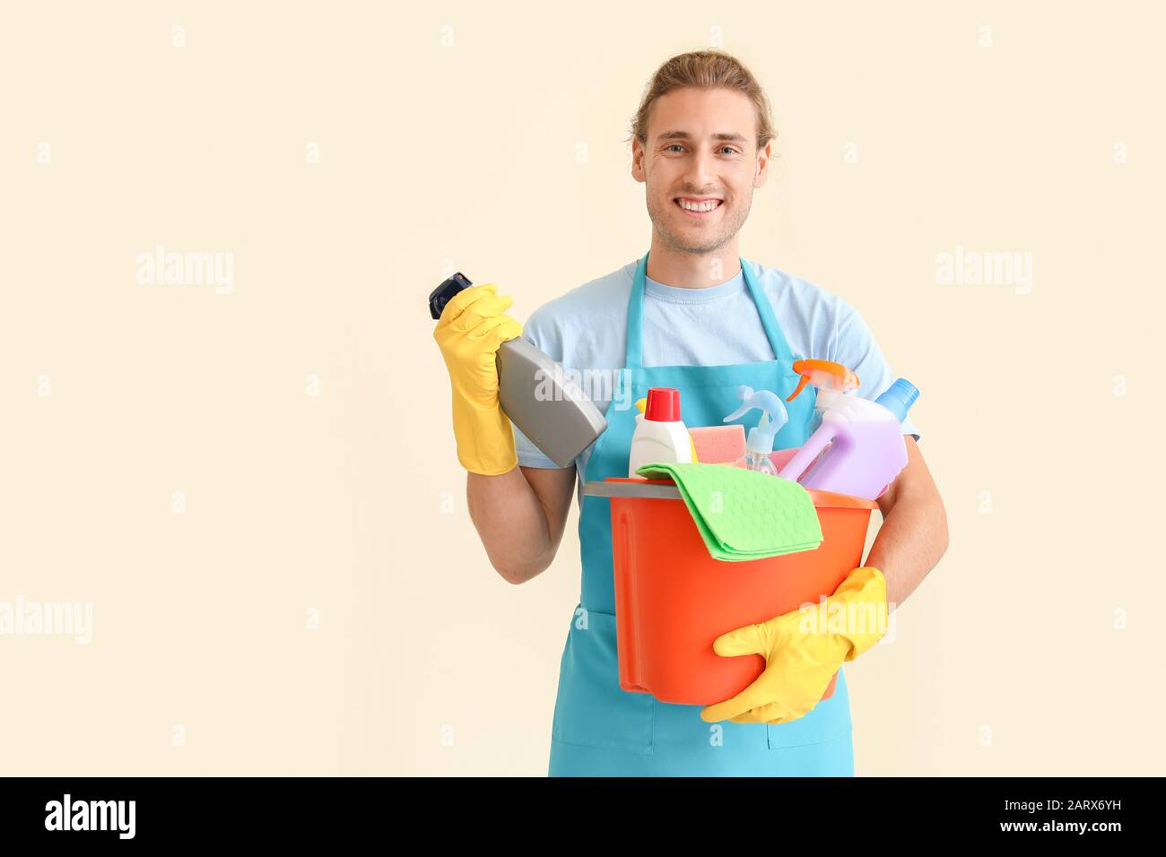 Male janitor with cleaning supplies on light background Stock Photo - Alamy