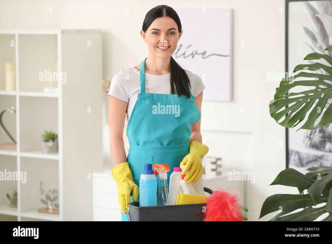 Female janitor with cleaning supplies in room Stock Photo - Alamy