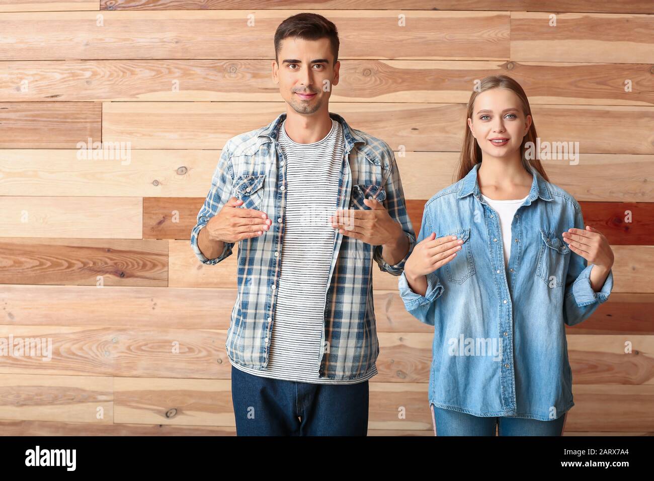 Young deaf mute couple using sign language on wooden background Stock ...