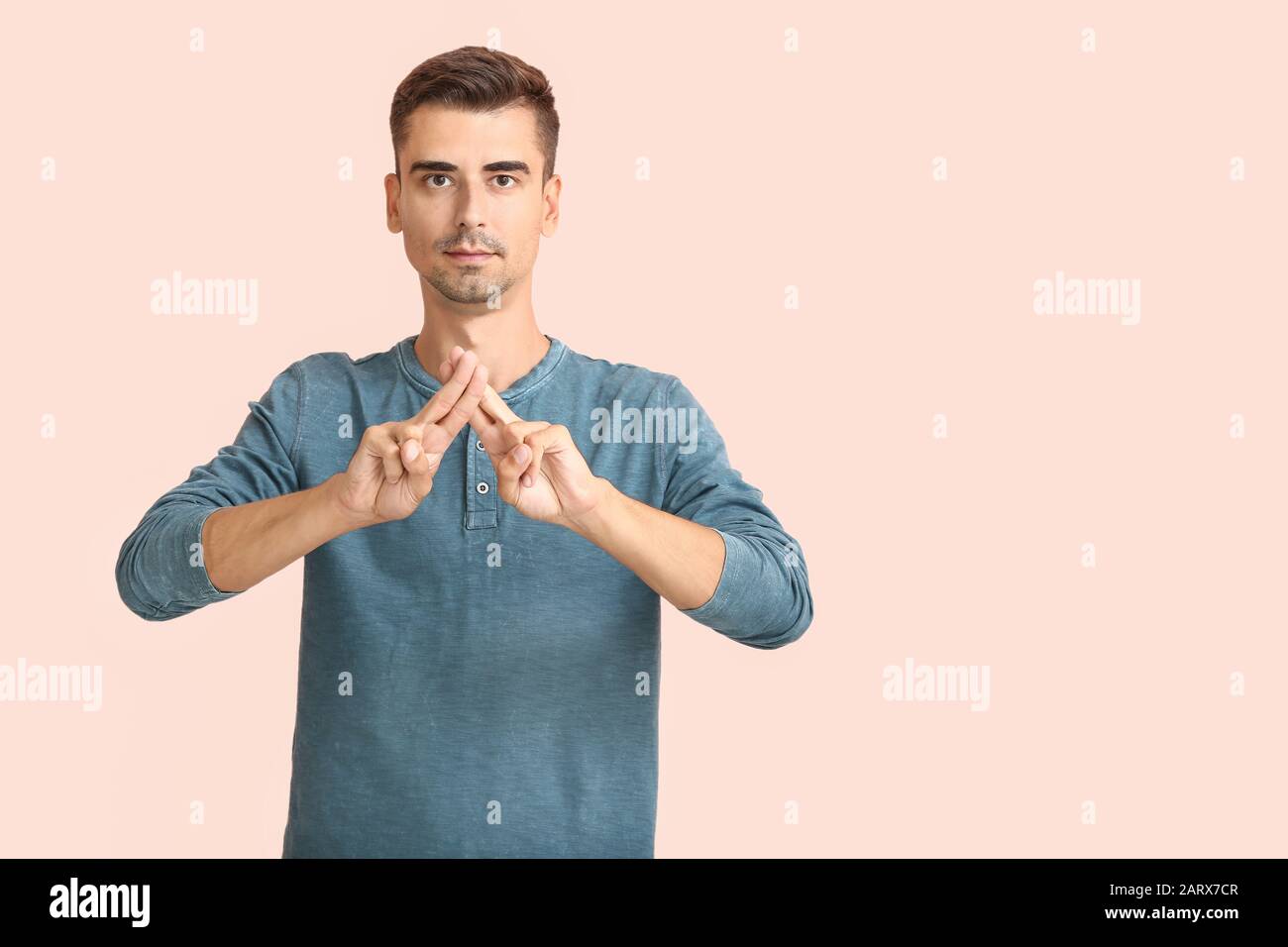 Young deaf mute man using sign language on color background Stock Photo ...