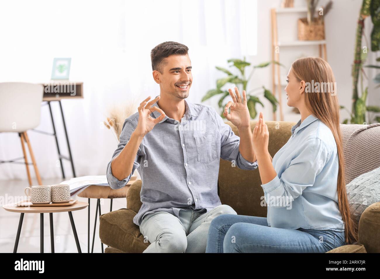 Young deaf mute couple using sign language at home Stock Photo - Alamy