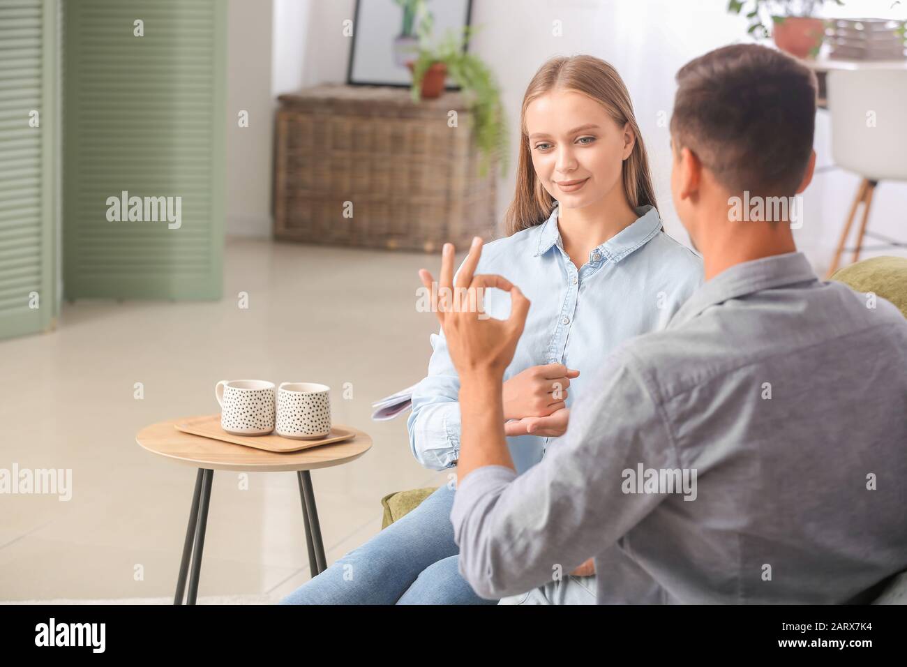 Young deaf mute couple using sign language at home Stock Photo - Alamy