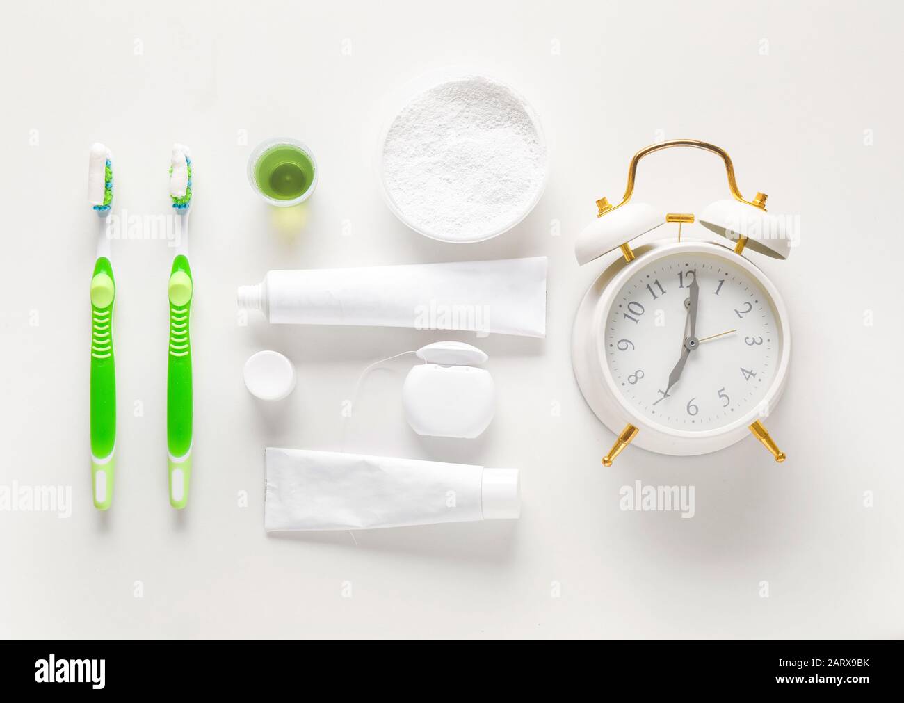 Set for dental hygiene and clock on light background Stock Photo - Alamy