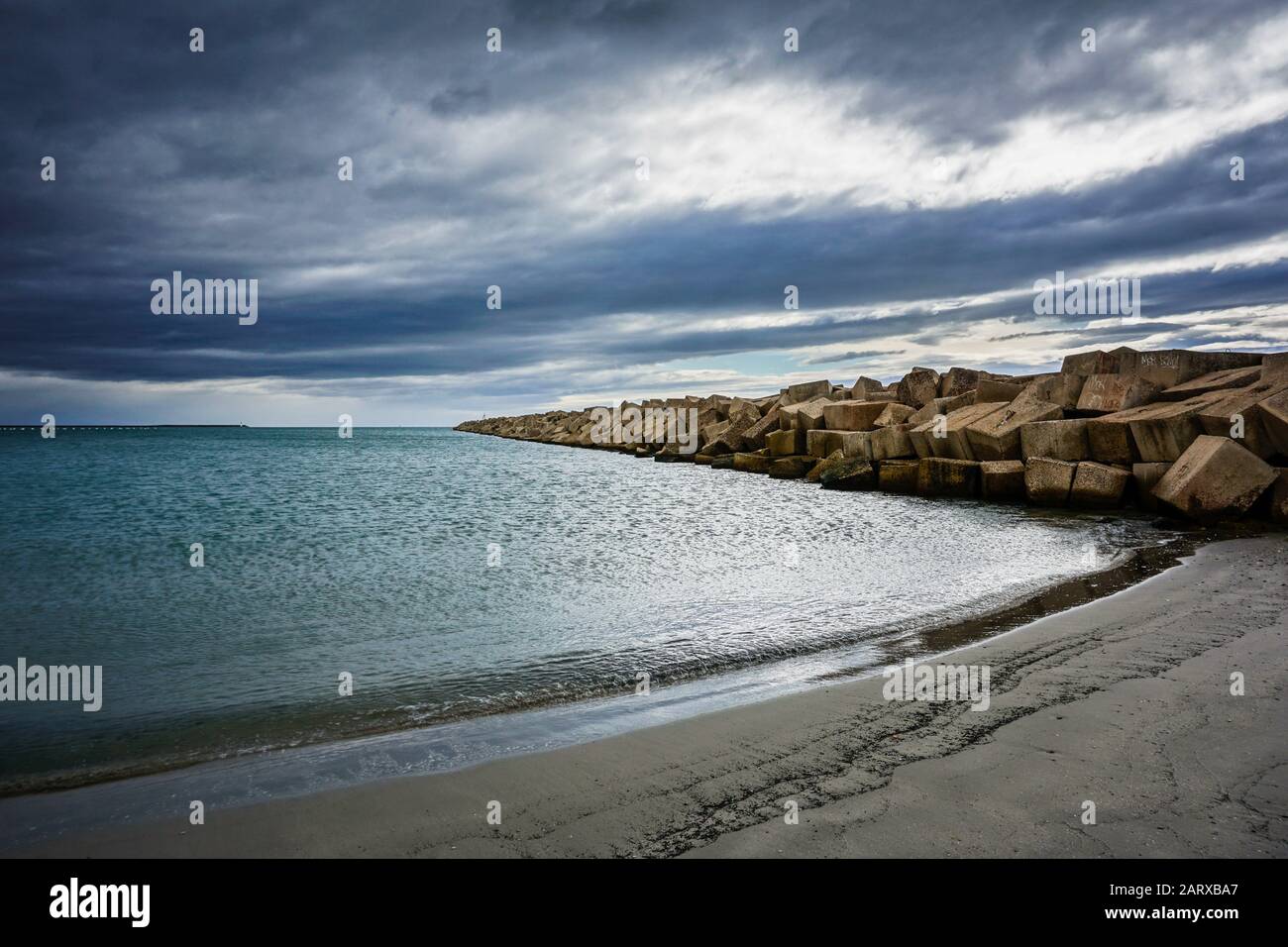 Moody Beach with wave barrier with bad weather Stock Photo - Alamy