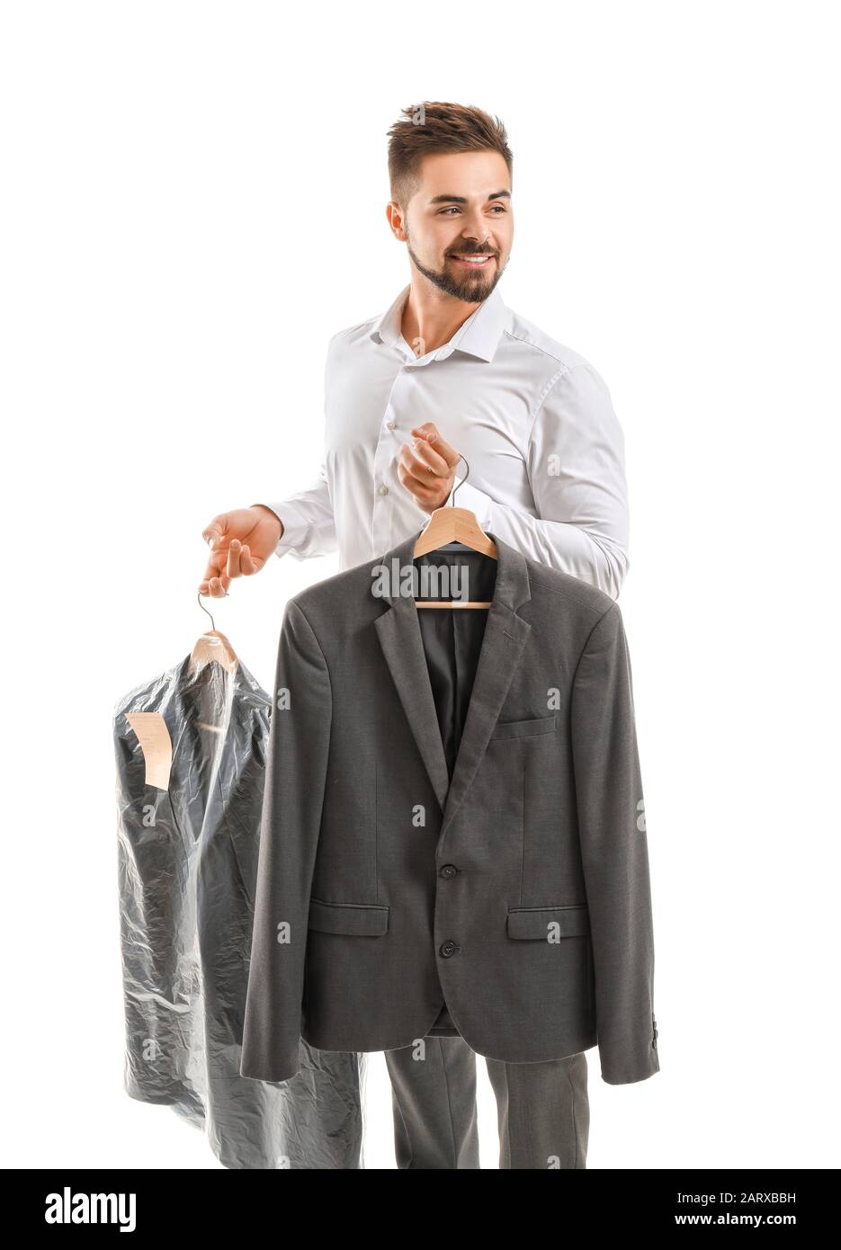Male worker of modern dry-cleaner with clothes on white background ...