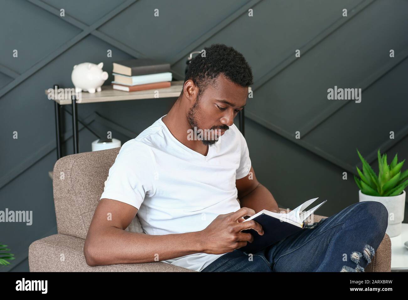 Handsome African-American man reading book at home Stock Photo - Alamy