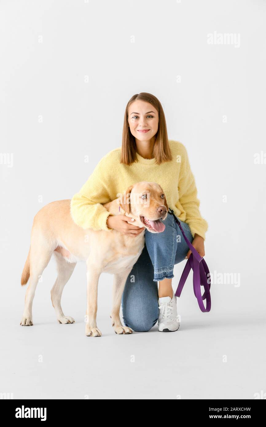 Beautiful young woman with cute dog on light background Stock Photo - Alamy