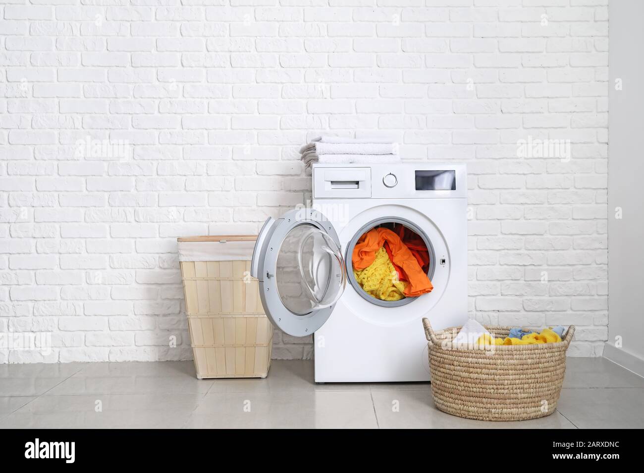Modern washing machine with laundry near white brick wall Stock Photo ...