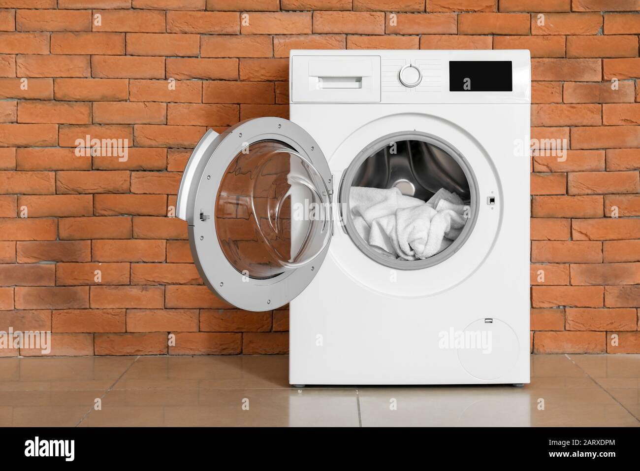 Modern washing machine with laundry near brick wall Stock Photo - Alamy