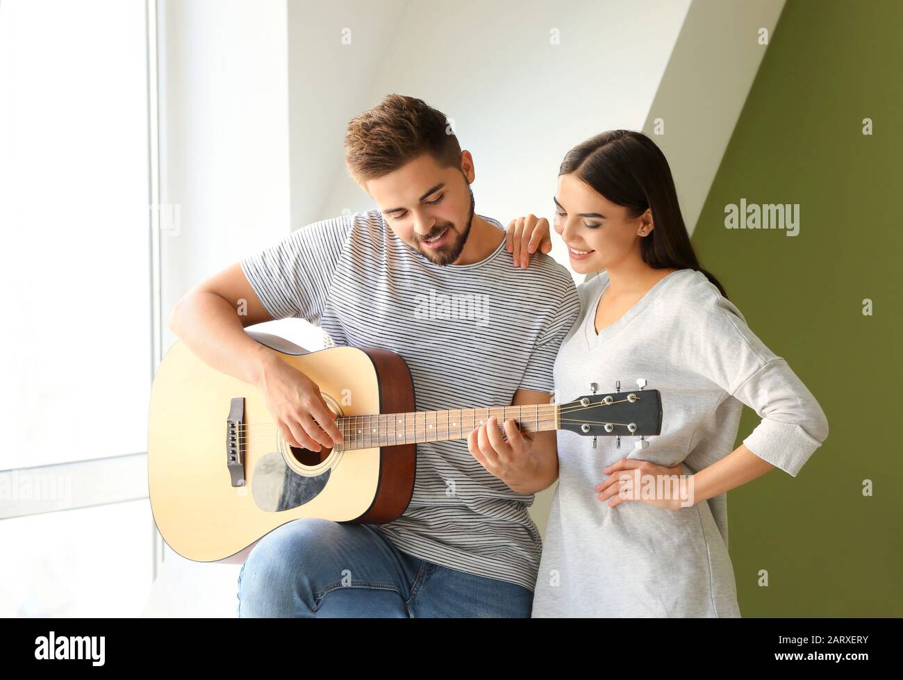 Beautiful young couple playing guitar at home Stock Photo - Alamy