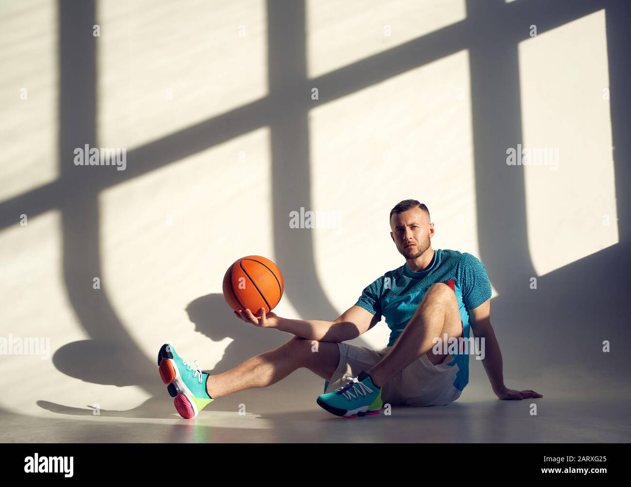 Young athletic man, basketball player holding ball with one hand and ...