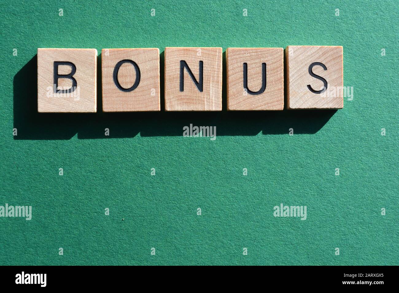 Bonus, word in 3d wooden alphabet letters on green background with copy ...