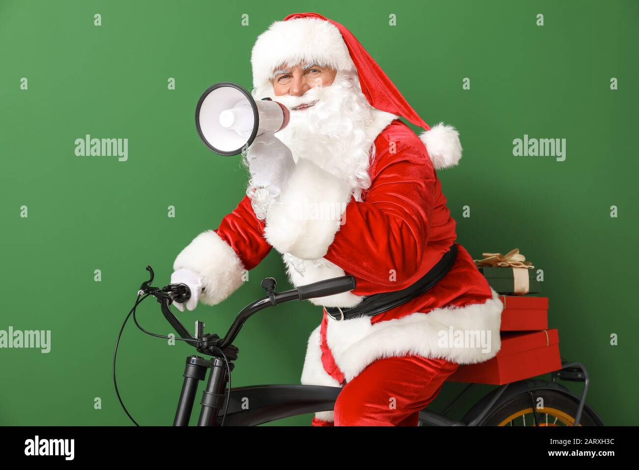 Santa Claus with megaphone and bicycle on color background Stock Photo ...