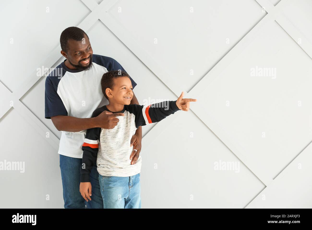 Portrait of African-American man with his little son pointing at ...