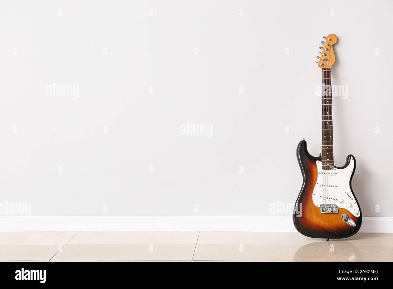 Modern bass guitar near white wall Stock Photo - Alamy