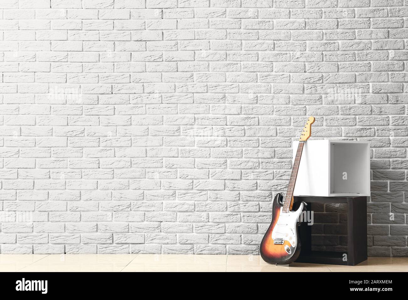 Modern bass guitar near white brick wall Stock Photo - Alamy